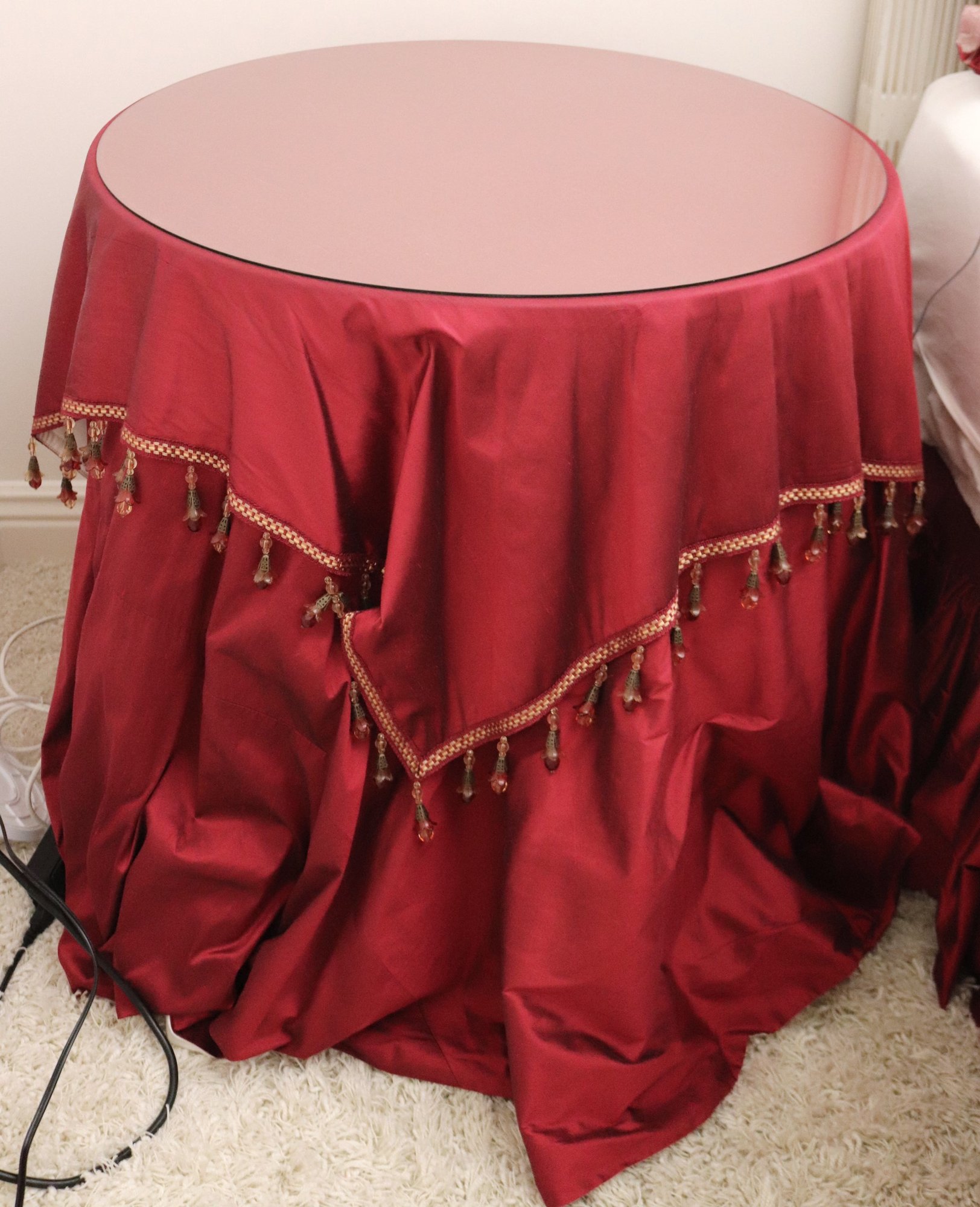 Round Plywood Table With Custom Red Silk Tablecloth And Fringed Red ...